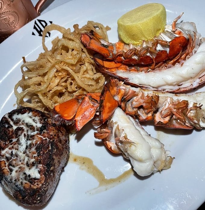 The surf and turf arrives like a celebrity power couple – the steak perfectly seared, the lobster tail ready for its butter bath, and those crispy onions stealing scenes.
