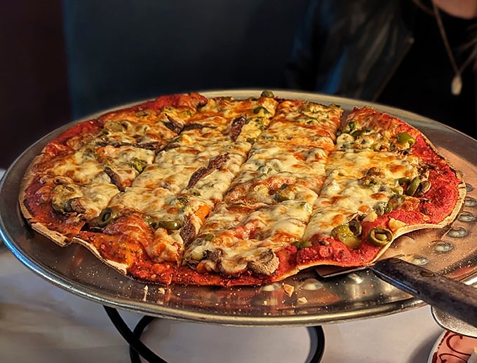 Behold the star attraction: tavern-style pizza cut into squares, with that perfect edge-to-edge cheese and a crust that somehow manages to be both crisp and yielding.