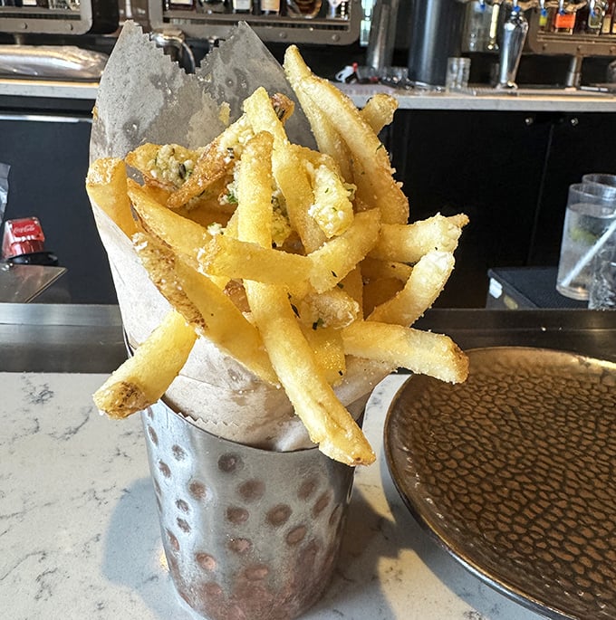 These aren't just fries—they're a golden treasure chest of crispy potato perfection. Served in a metal cup because paper would simply be undignified.