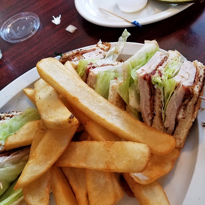 This turkey club isn't just stacked—it's architectural genius with layers of real roasted turkey, crisp bacon, and fresh veggies that make every bite a celebration.