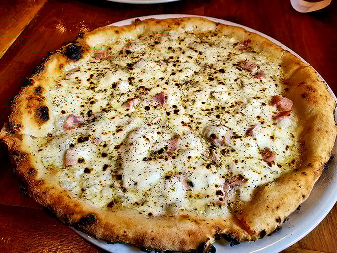 This white pizza with its perfectly charred crust and delicate toppings isn't just food – it's edible architecture with a PhD in deliciousness.