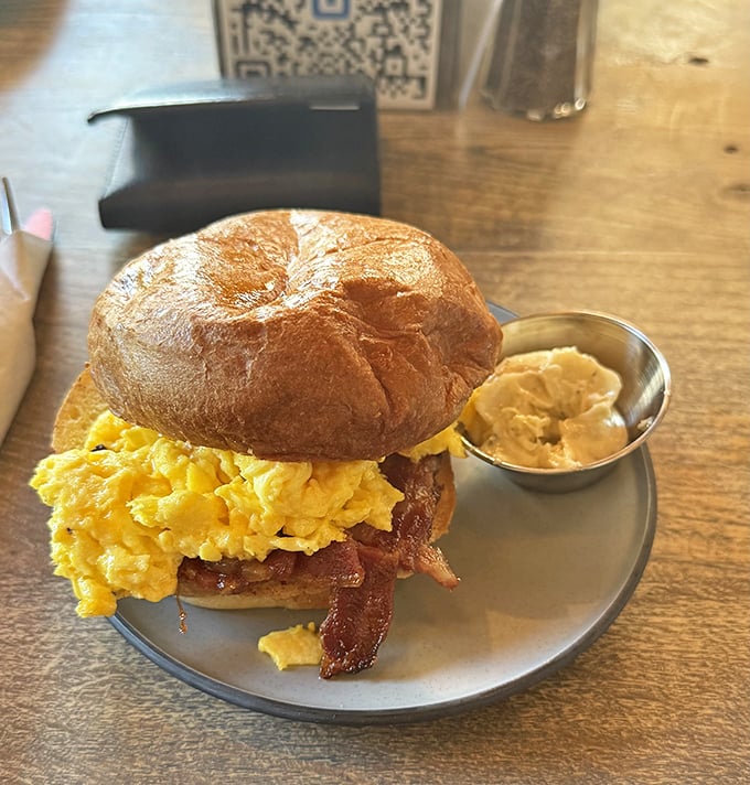 Behold the breakfast sandwich in its natural habitat—golden eggs cascading over crispy bacon on a perfectly toasted brioche bun. Resistance is futile.