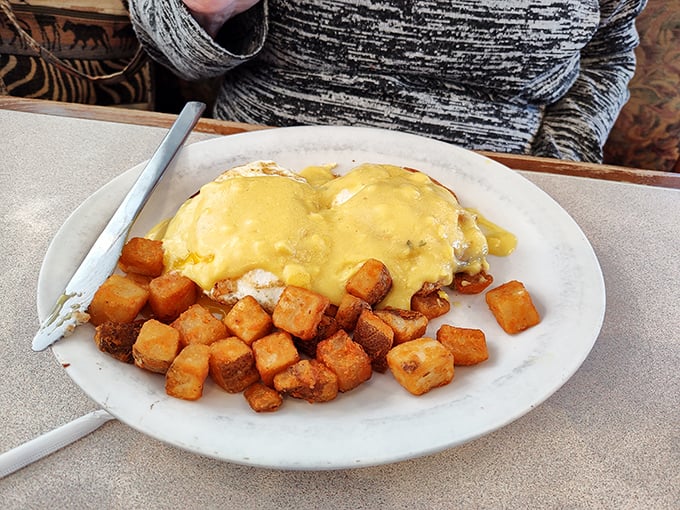 Eggs Benedict done right is breakfast's greatest magic trick—perfectly poached eggs under a golden hollandaise blanket with home fries that demand equal attention.
