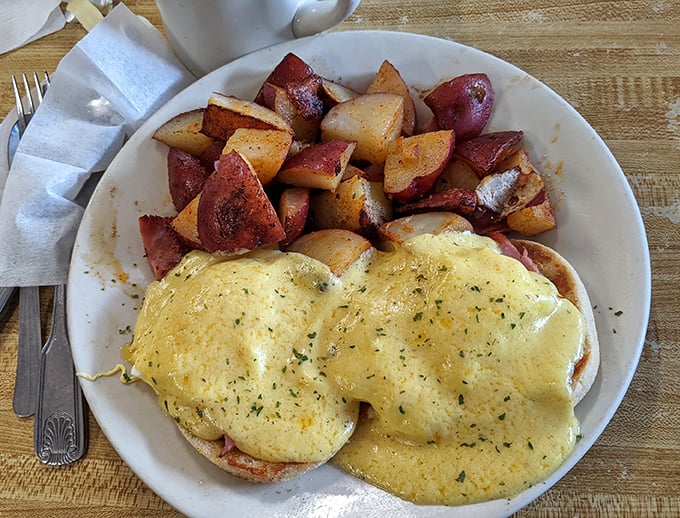 These eggs Benedict aren't just breakfast—they're a masterclass in hollandaise architecture, perfectly cascading over English muffins alongside home fries that mean business.