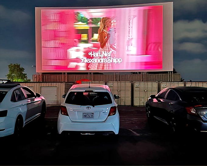 As darkness falls, the massive screen illuminates with vibrant color, turning ordinary cars into private viewing boxes under the San Diego sky.