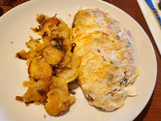 Behold the perfect omelet—fluffy on the outside, packed with goodness inside. Paired with those golden home fries, it's breakfast nirvana on a plate.