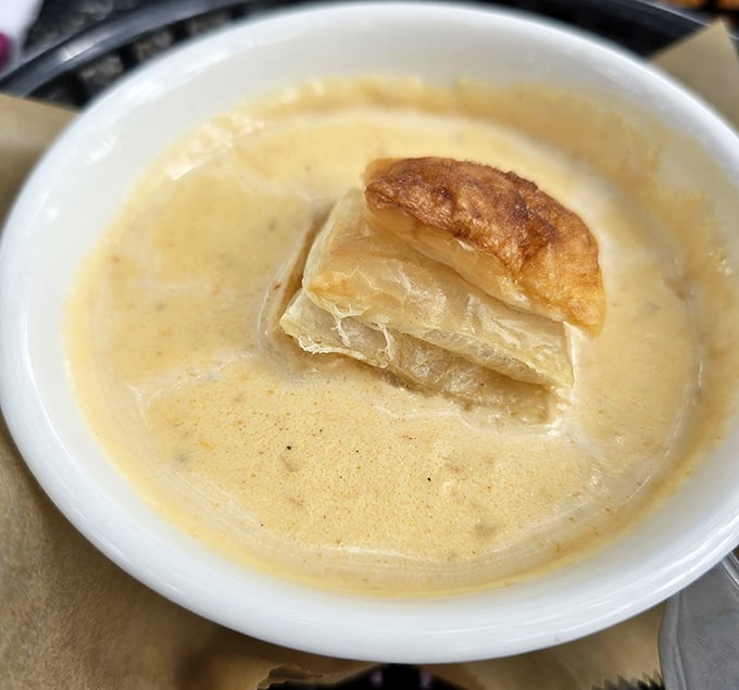 The She Crab Soup arrives like a warm hug in a bowl, crowned with a golden puff pastry island waiting to be submerged.