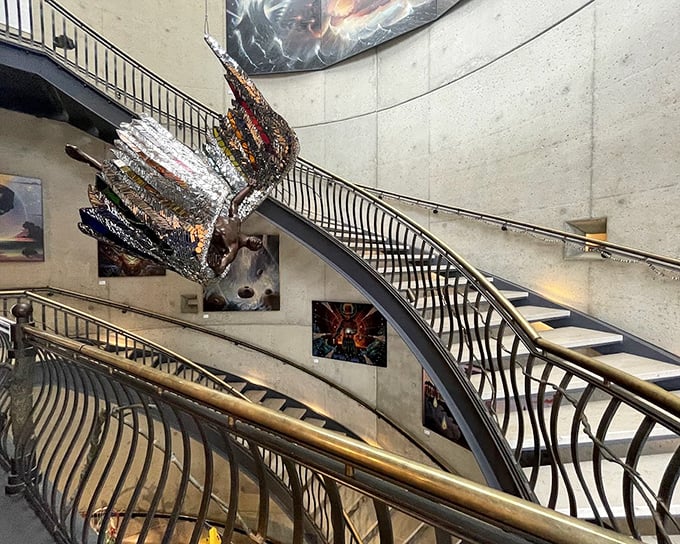 The sweeping staircase isn't just functional—it's a sculptural journey upward, with art suspended in mid-air like creative constellations.