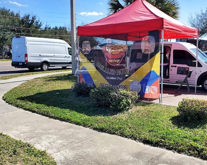 Colombian-style hot dog magic happens under this unassuming red tent – proof that culinary treasures often hide in plain sight.