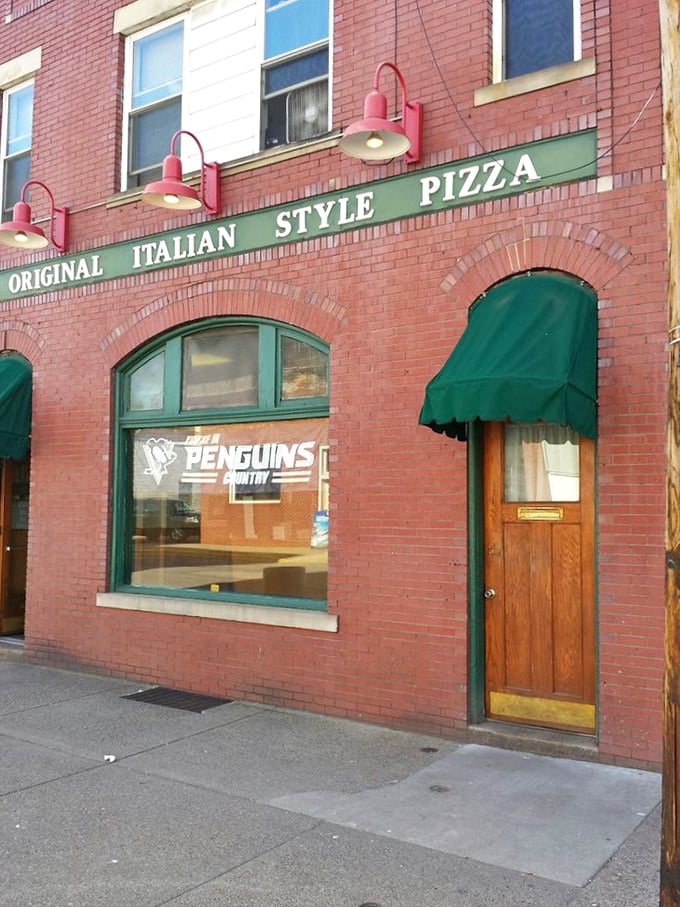 Green awnings frame windows that reveal the kind of pizza dreams are absolutely made of.