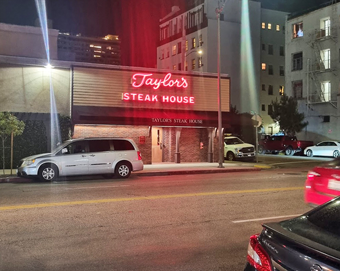 The classic neon sign at Taylor's glows like a beacon in the night, promising old-school steakhouse perfection.