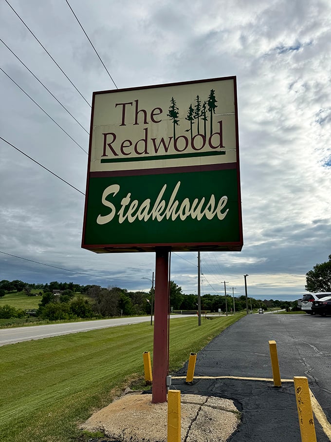 That classic Redwood sign stands tall against Iowa skies – promising steaks worth the drive and a salad bar that's actually worth visiting.