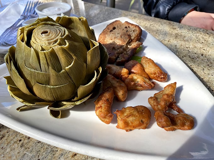The steamed artichoke arrives like royalty on its throne, accompanied by golden fried artichoke hearts that crunch with satisfying perfection.