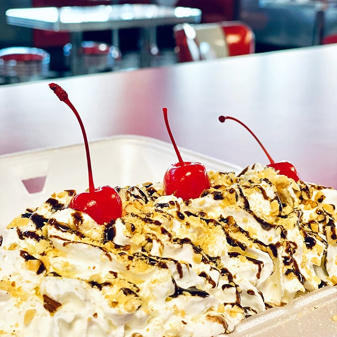 Three cherries standing guard over whipped cream mountains and chocolate rivers – dessert that demands respect and spoons.