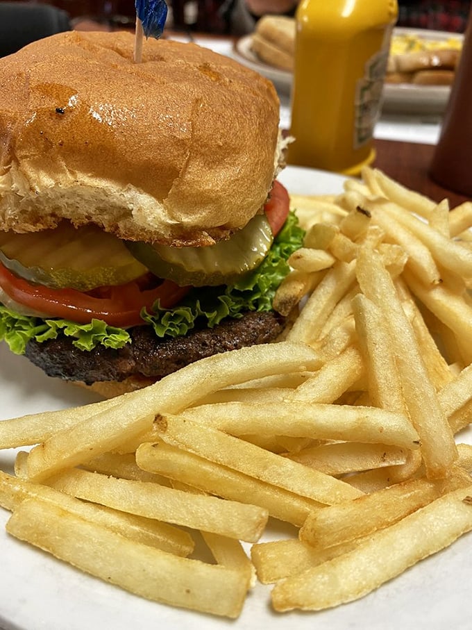 This isn't just a burger—it's edible architecture. Golden fries standing at attention beside a tower of beef, veggies, and bun that demands a strategic attack plan.