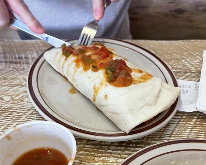 Behold the breakfast burrito in its natural habitat – a flour tortilla masterpiece topped with just enough chile to make you feel alive.