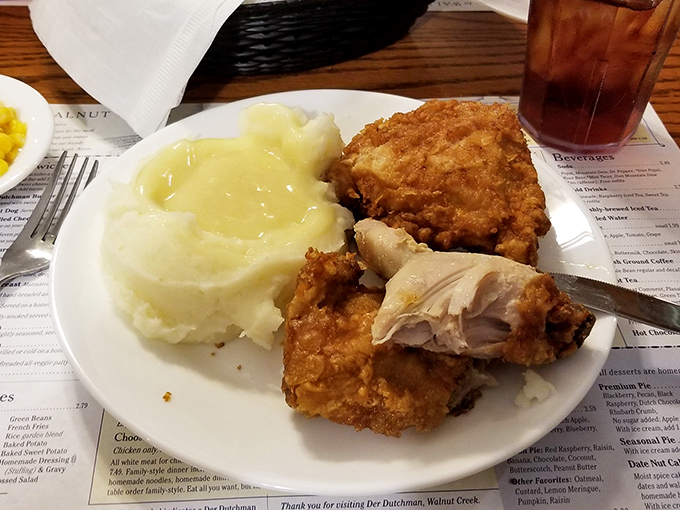 Broasted chicken so perfectly golden it belongs in a museum, paired with mashed potatoes drowning happily in gravy – a plate of Midwestern happiness.