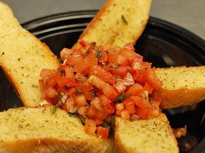 This bruschetta doesn't whisper "fresh" – it shouts it from the rooftops with diced tomatoes and herbs perched atop perfectly toasted garlic bread triangles.