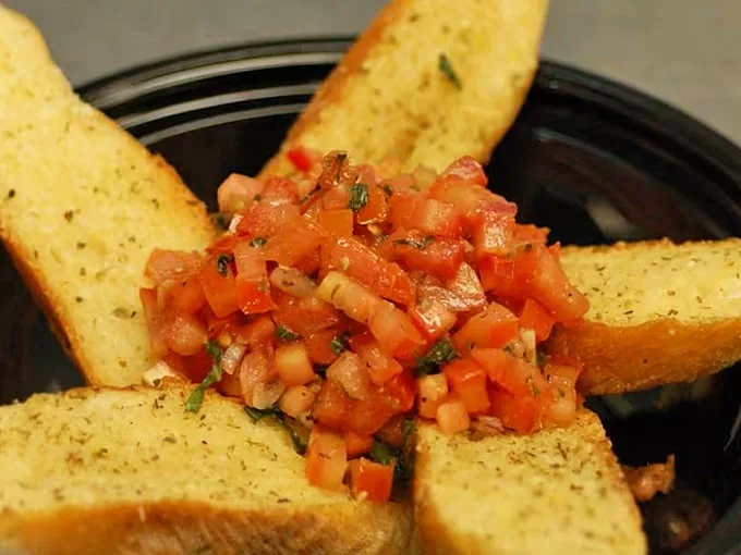 This bruschetta doesn't whisper "fresh" – it shouts it from the rooftops with diced tomatoes and herbs perched atop perfectly toasted garlic bread triangles.