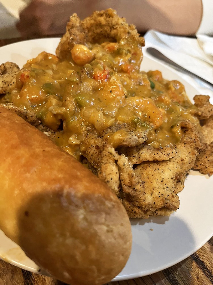 The Catfish Perdu doesn't just sit on your plate – it lounges luxuriously under a blanket of crawfish étouffée like it's at a seafood spa.