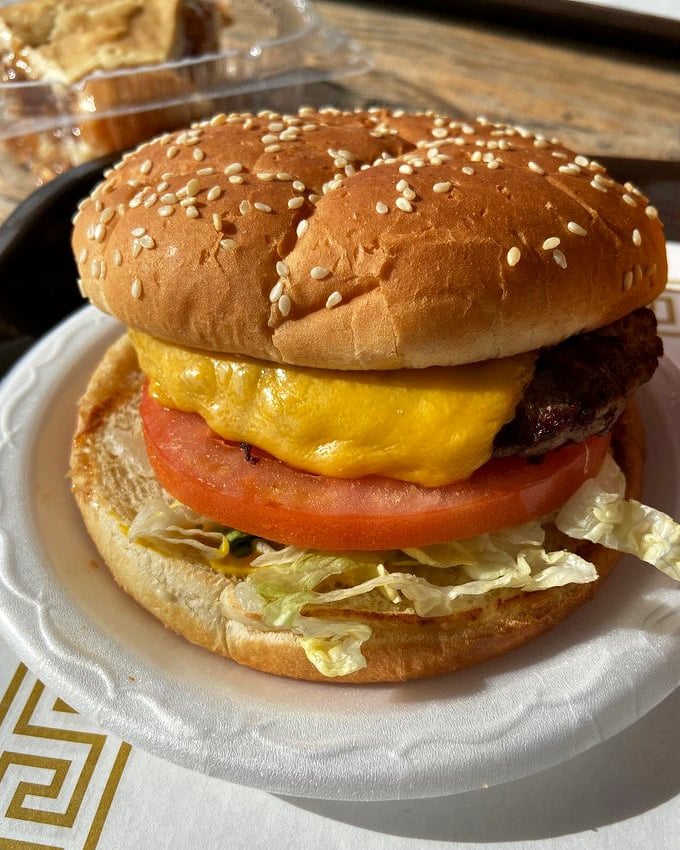 This isn't just a cheeseburger—it's edible architecture with layers of fresh lettuce, tomato, and melted cheese that cascades over the patty.