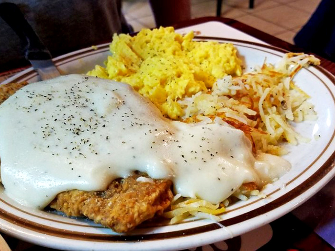Country fried steak smothered in gravy with eggs and hash browns—the breakfast equivalent of a warm hug from someone who truly understands you.