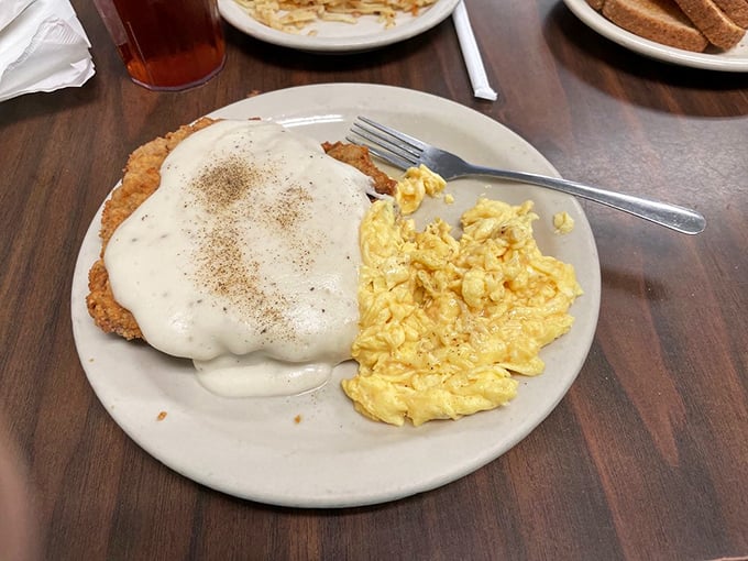 Chicken fried steak that extends beyond the plate's boundaries, smothered in peppery cream gravy—a Texas tradition that requires both a fork and a commitment.