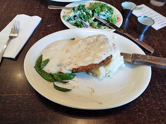 This chicken fried steak isn't just covered in gravy—it's blanketed in creamy, peppery comfort with a side of snap peas that somehow make you feel virtuous.