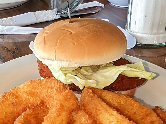 This chicken sandwich with its golden-fried crust isn't just food—it's armor against a bad day, complete with crispy sidekicks standing guard.
