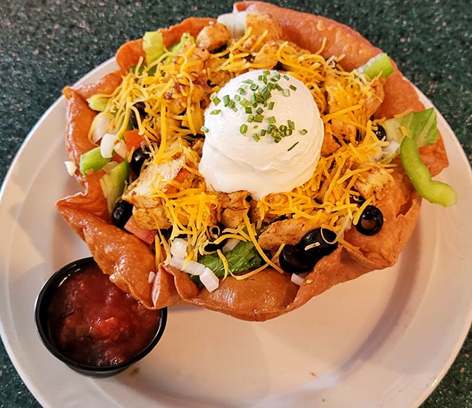 The chicken taco salad arrives like edible architecture—a crispy tortilla bowl cradling seasoned chicken, cheese, and veggies, crowned with a dollop of sour cream.