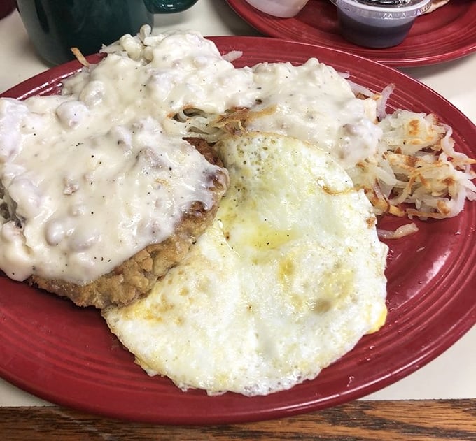 Country fried steak smothered in creamy gravy alongside sunny-side-up eggs and crispy hash browns—the breakfast trifecta that makes morning people out of night owls.