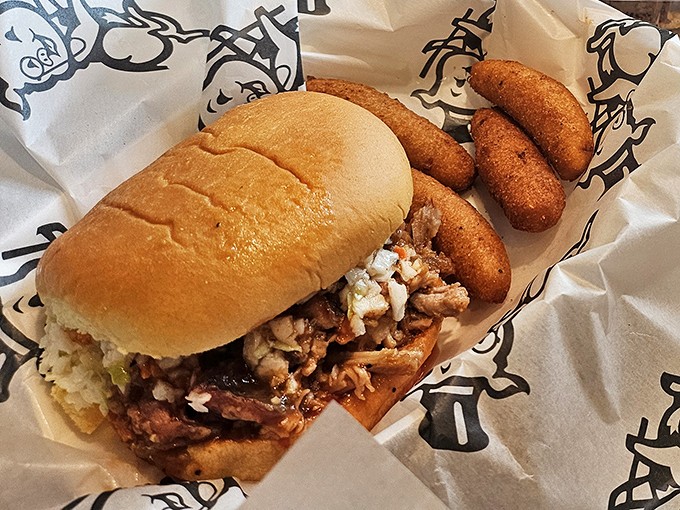 The chopped barbecue sandwich—North Carolina's greatest contribution to handheld happiness, accompanied by hush puppies that deserve their own fan club.