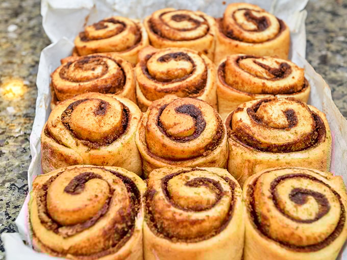 Fresh cinnamon rolls lined up like sweet soldiers awaiting their caramel bath. Resistance is futile, surrender is delicious.