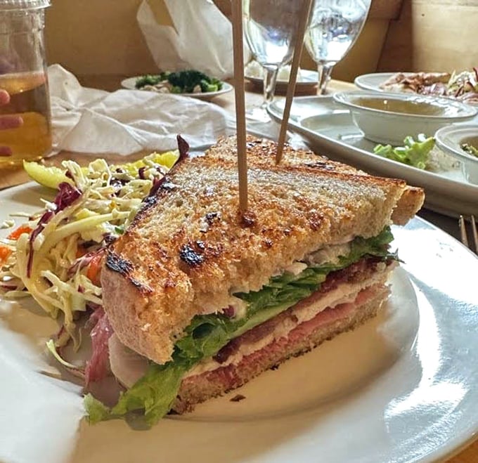Behold the club sandwich in its natural habitat—stacked tall enough to require strategic first-bite planning, with slaw that isn't an afterthought.