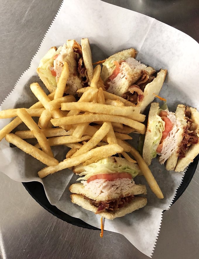 A club sandwich that doesn't mess around—stacked high with layers of goodness and accompanied by golden fries that could make a potato farmer weep with pride.