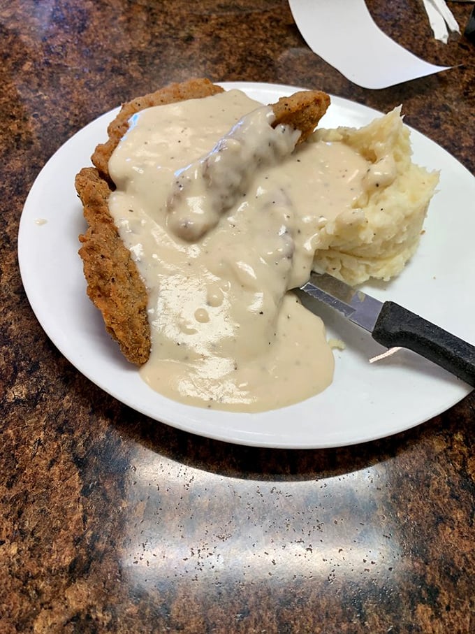 This country fried steak doesn't just come with gravy—it swims in it gloriously, with mashed potatoes standing by as willing accomplices to deliciousness.
