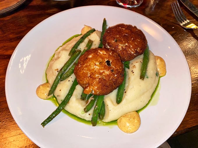 These crab cakes aren't playing around—perched atop creamy mashed potatoes with green beans standing at attention like tasty little soldiers.