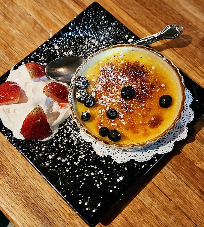 This crème brûlée's perfectly torched top cracks like thin ice on a winter pond, revealing silky custard beneath—a sweet finale worth saving room for.