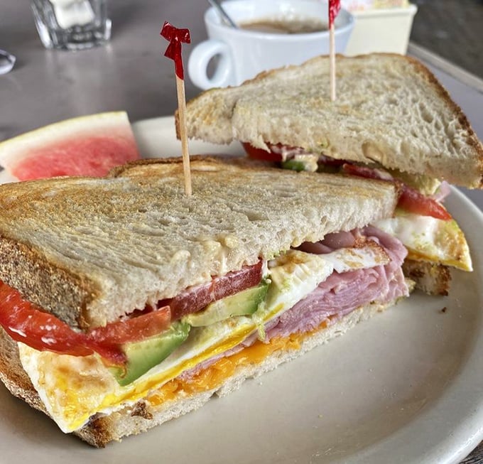Sandwich architecture at its finest – layers of egg, ham, and fresh vegetables stacked with the precision of a Jenga master who's also a flavor scientist.