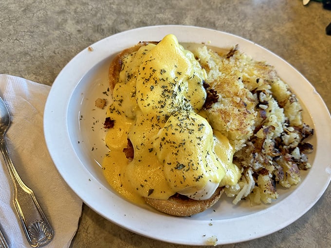 Eggs Benedict done right—a perfect hollandaise cascade over poached eggs with hash browns that achieve that magical crispy-outside, tender-inside perfection.