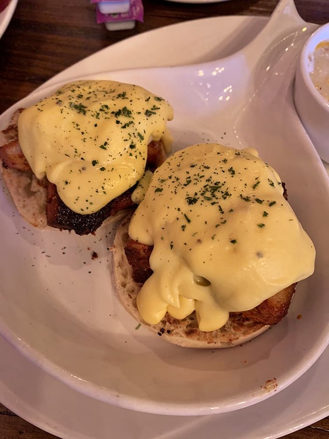 Eggs Benedict done right—English muffins supporting perfectly poached eggs beneath a sunshine-yellow hollandaise blanket. Breakfast architecture at its finest.