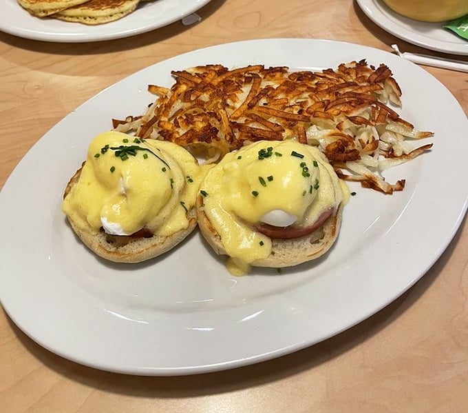 Eggs Benedict done right—perfectly poached eggs nestled on Canadian bacon, draped in hollandaise that cascades like a yellow waterfall of deliciousness.