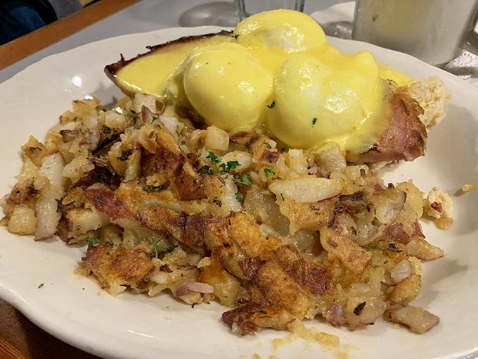 Eggs benedict over crispy hash browns with hollandaise that cascades like a delicious yellow waterfall—breakfast engineering at its finest right here.