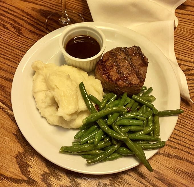 The filet mignon arrives like a dignified gentleman – compact, well-dressed, and surrounded by excellent company of mashed potatoes and green beans.
