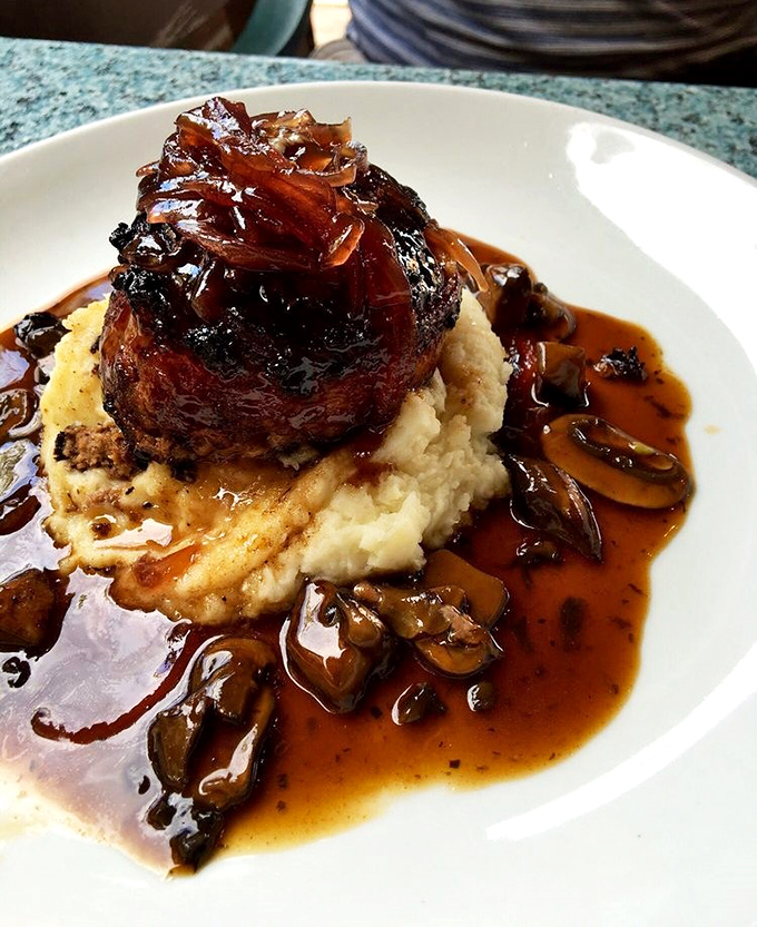 A filet mignon atop creamy mashed potatoes with mushroom sauce—proof that heaven exists and it's made of beef.