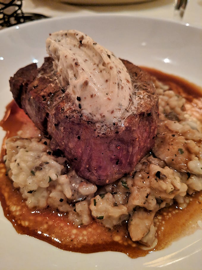 This filet mignon isn't just sitting on risotto—it's holding court, wearing a crown of compound butter that's melting into pure bliss.