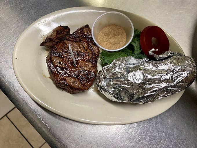 This filet mignon isn't just cooked—it's been treated with the reverence of a sacred artifact, complete with ceremonial baked potato in foil.