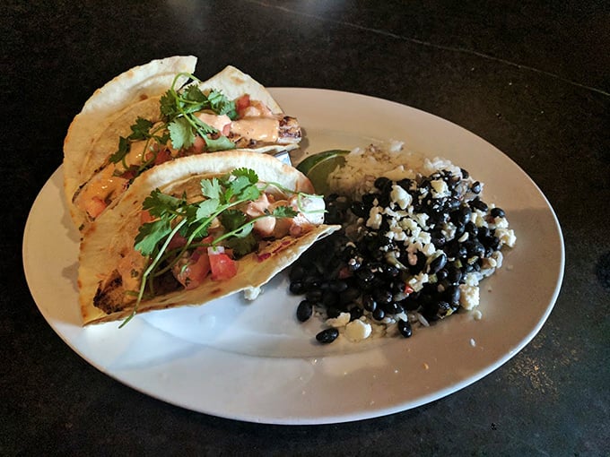 These aren't just fish tacos – they're flavor vessels sailing across a sea of black beans and rice, with cilantro as their proud flag.