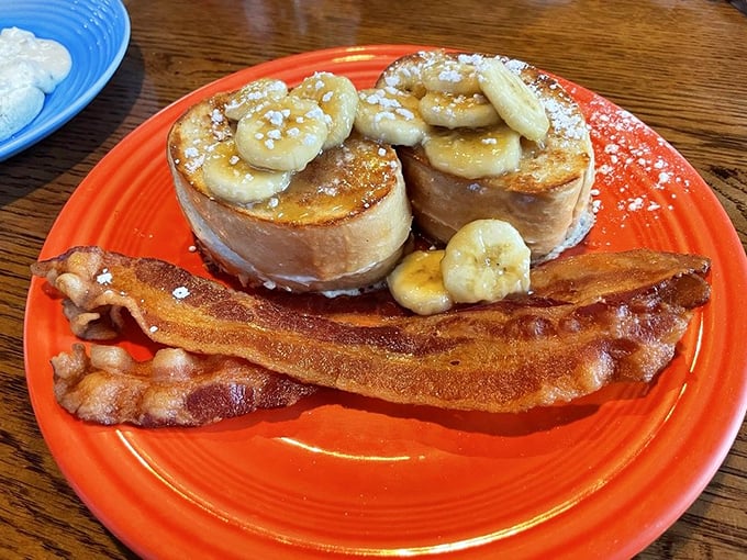 French toast elevated to art form—golden slices topped with caramelized bananas and a dusting of powdered sugar that would make even dessert jealous.