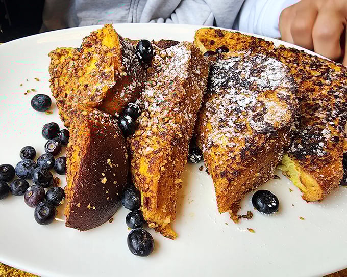 French toast that deserves its own Instagram account—golden-brown, dusted with powdered sugar, and surrounded by fresh blueberries like edible jewels.